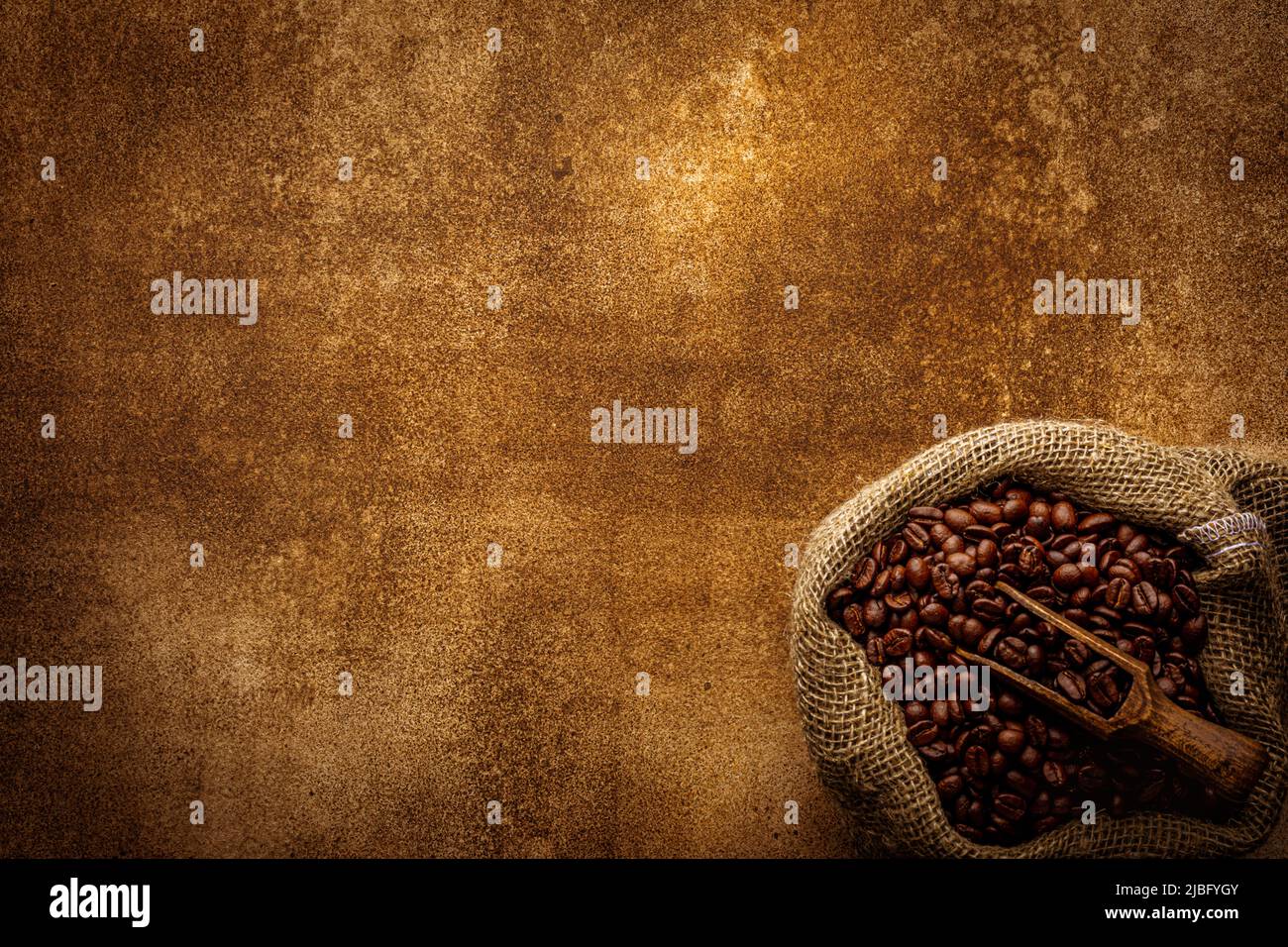 Coffee beans in burlap sack over horizontal grunge background with copy space. Concrete rustic ...