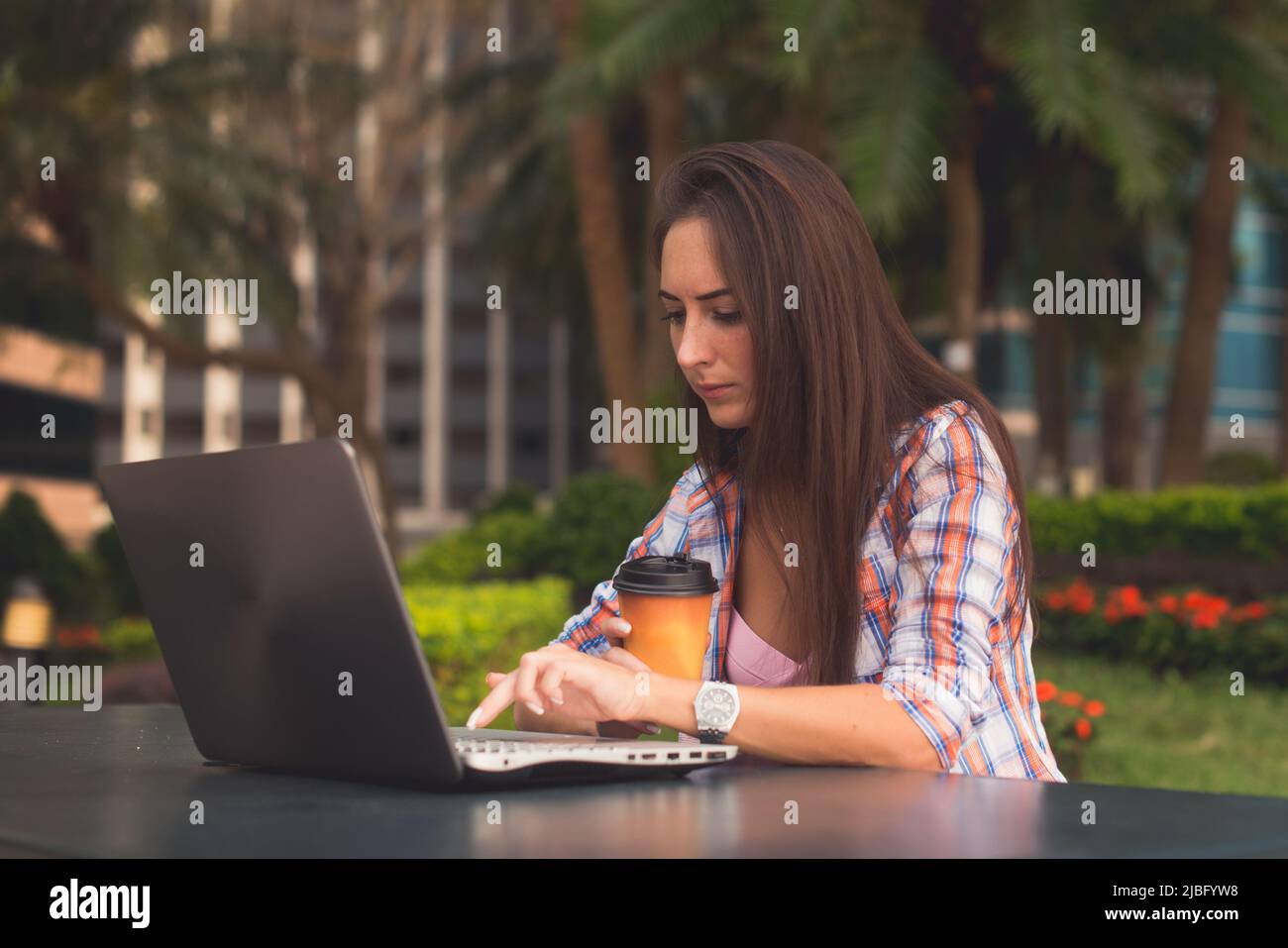 Young woman typing on her laptop working and drinking coffee in the ...