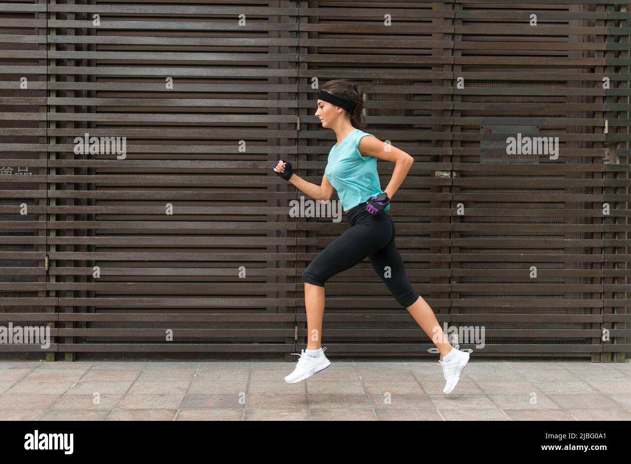 Side view of sporty young woman running on a sidewalk Stock Photo - Alamy