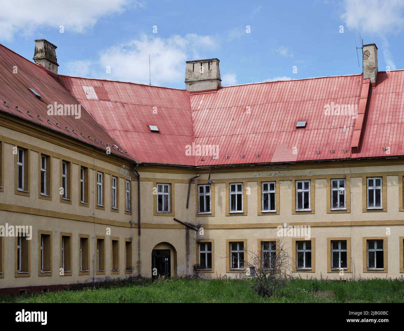 Abandoned ruined building with a red tin roof and three chimneys in the ...