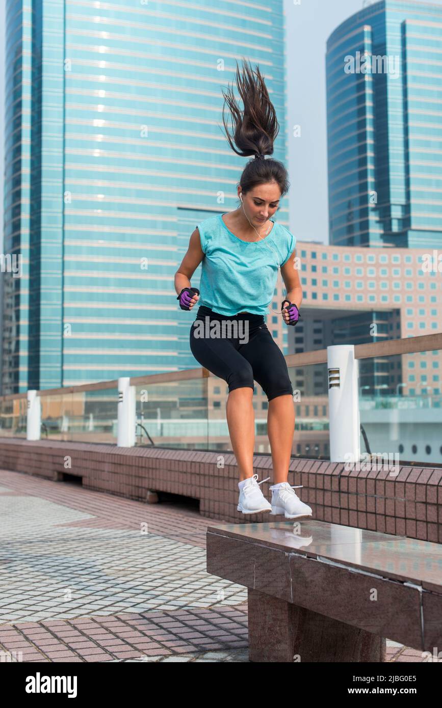 Young fit active woman bench jump squat jumping on city street. Fitness ...