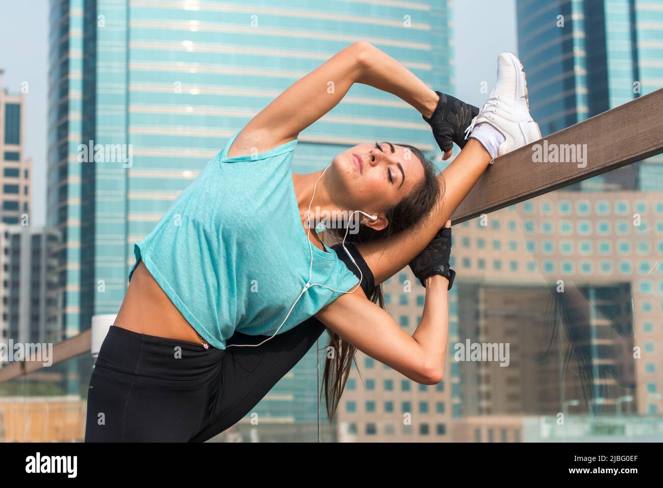 Young fitness woman doing standing split exercise on the city street ...
