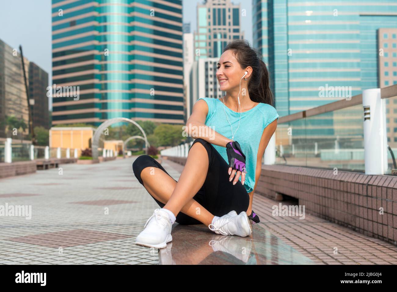 Young fitness woman resting after exercising, smiling, sitting at the ...