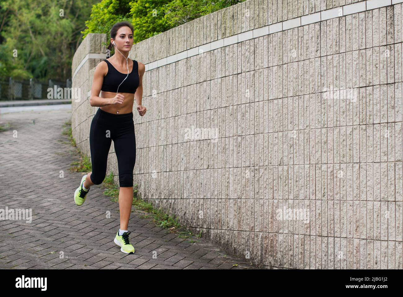 Fit young female jogger jogging on sidewalk in suburban area. Pretty ...