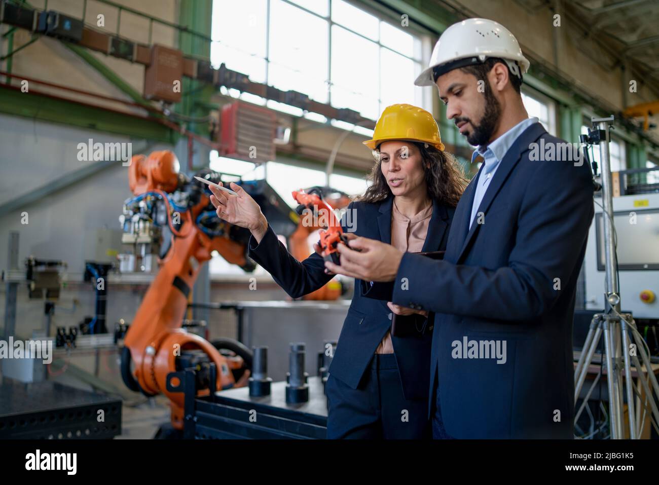 Man engineer holding model of industrial robotic arm and showing to ...