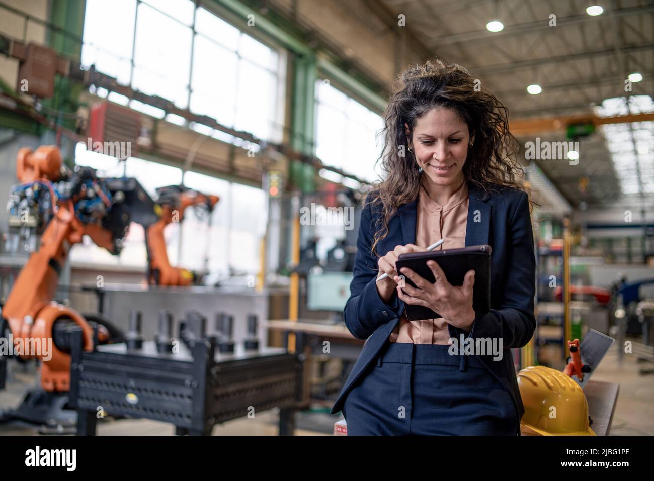 A portrait of female chief engineer in modern industrial factory using ...