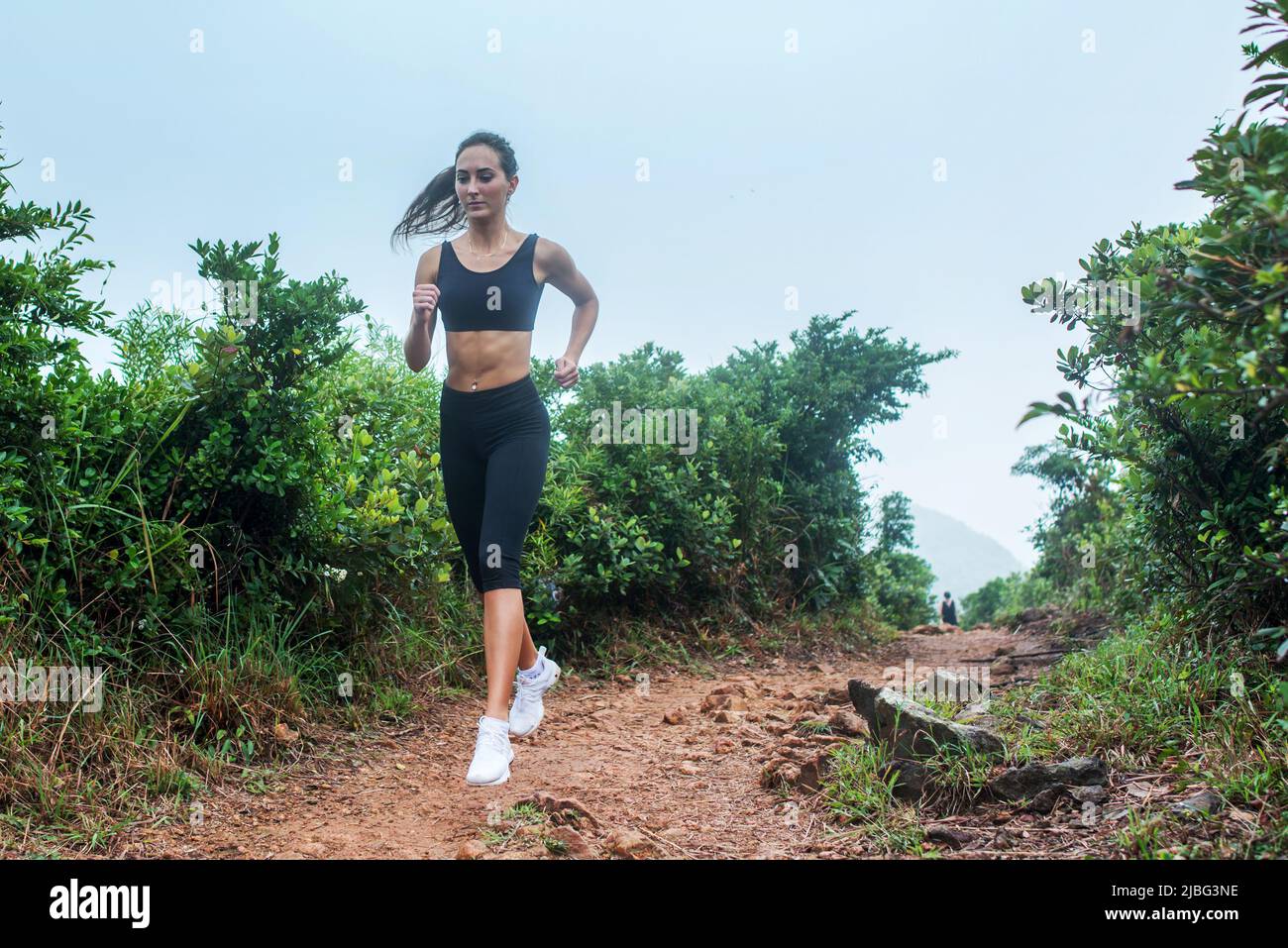 Fitness female athlete running on forest path in mountainous area in ...