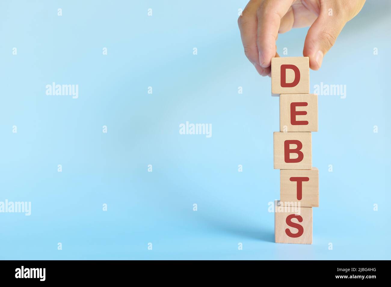 Human hand stacking word debts in wooden blocks. Growing financial debt ...