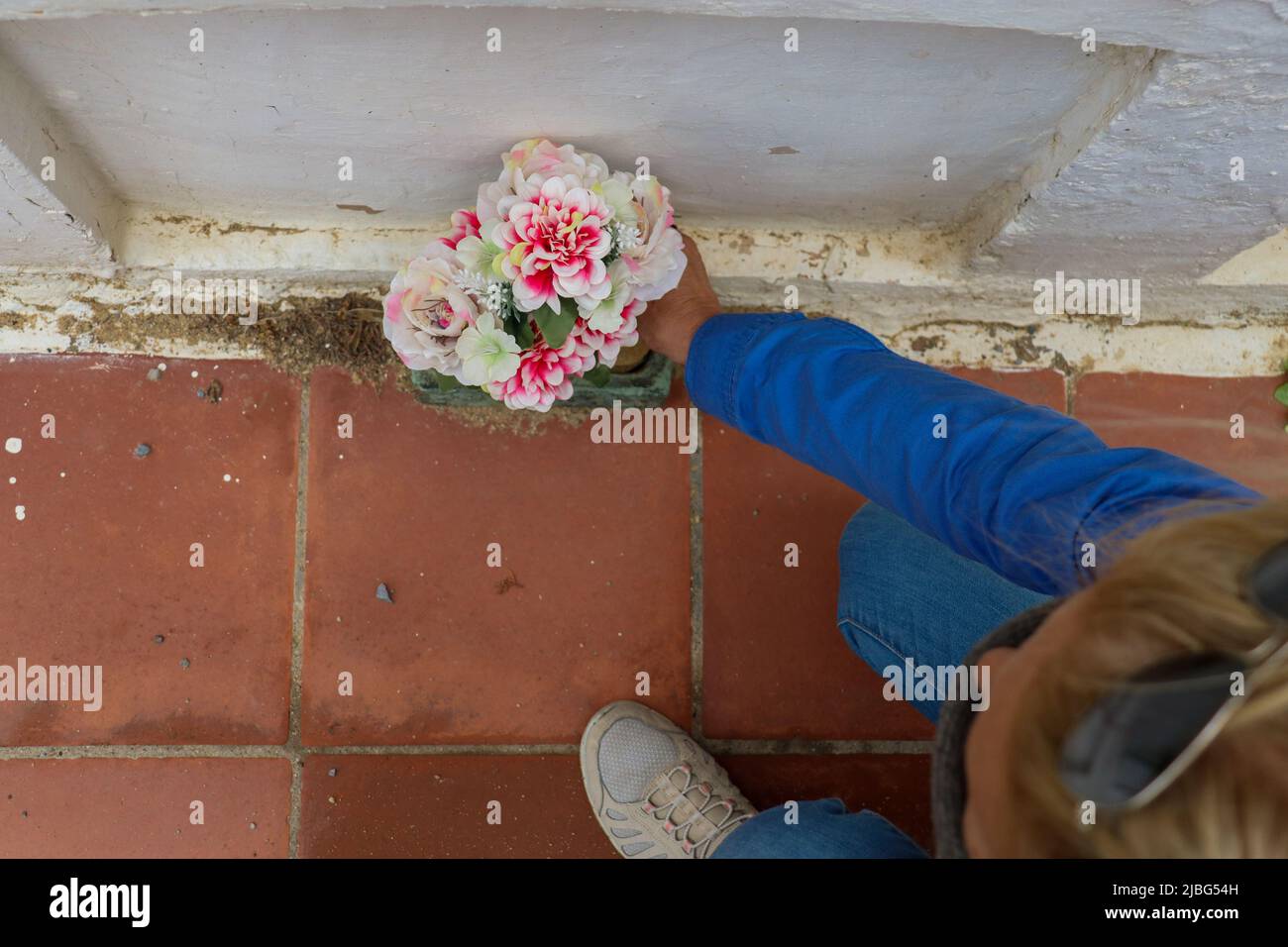 An unfocused woman touching some flowers in the graveyard Stock Photo ...