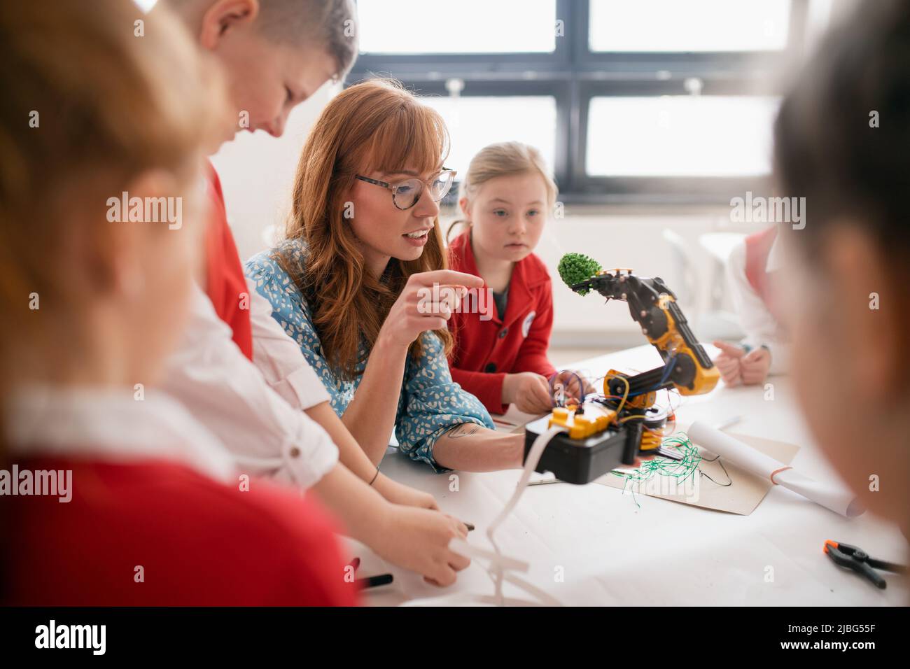 Group of kids with young science teacher programming electric toys and ...