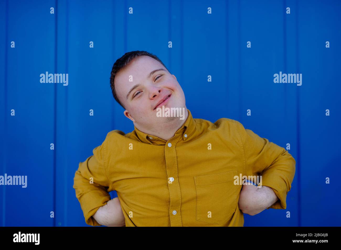 Happy young man with Down syndrome smiling and looking at camera ...