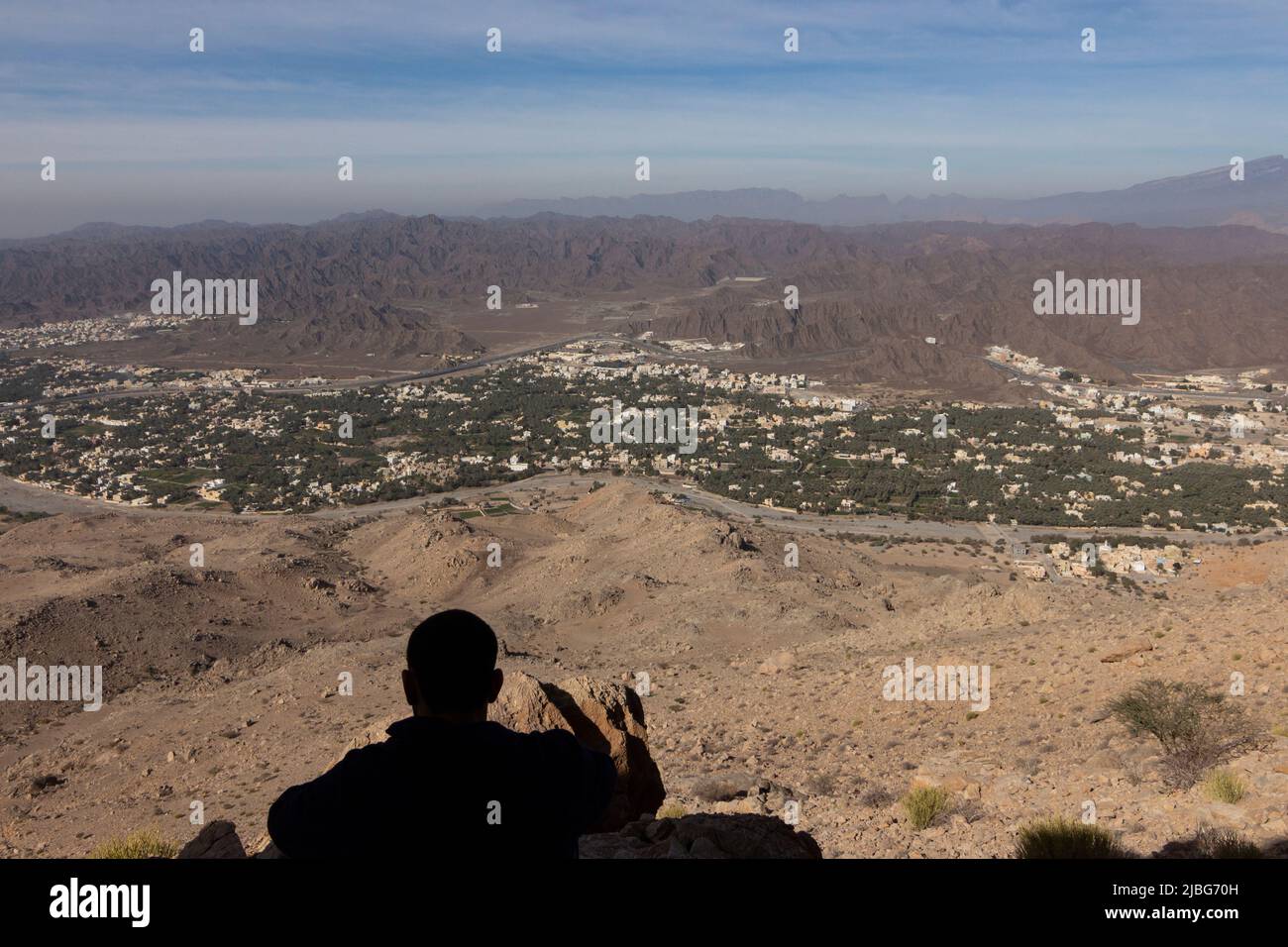 Silhouette of a man overlooking the city of Nizwa and its surrounding ...