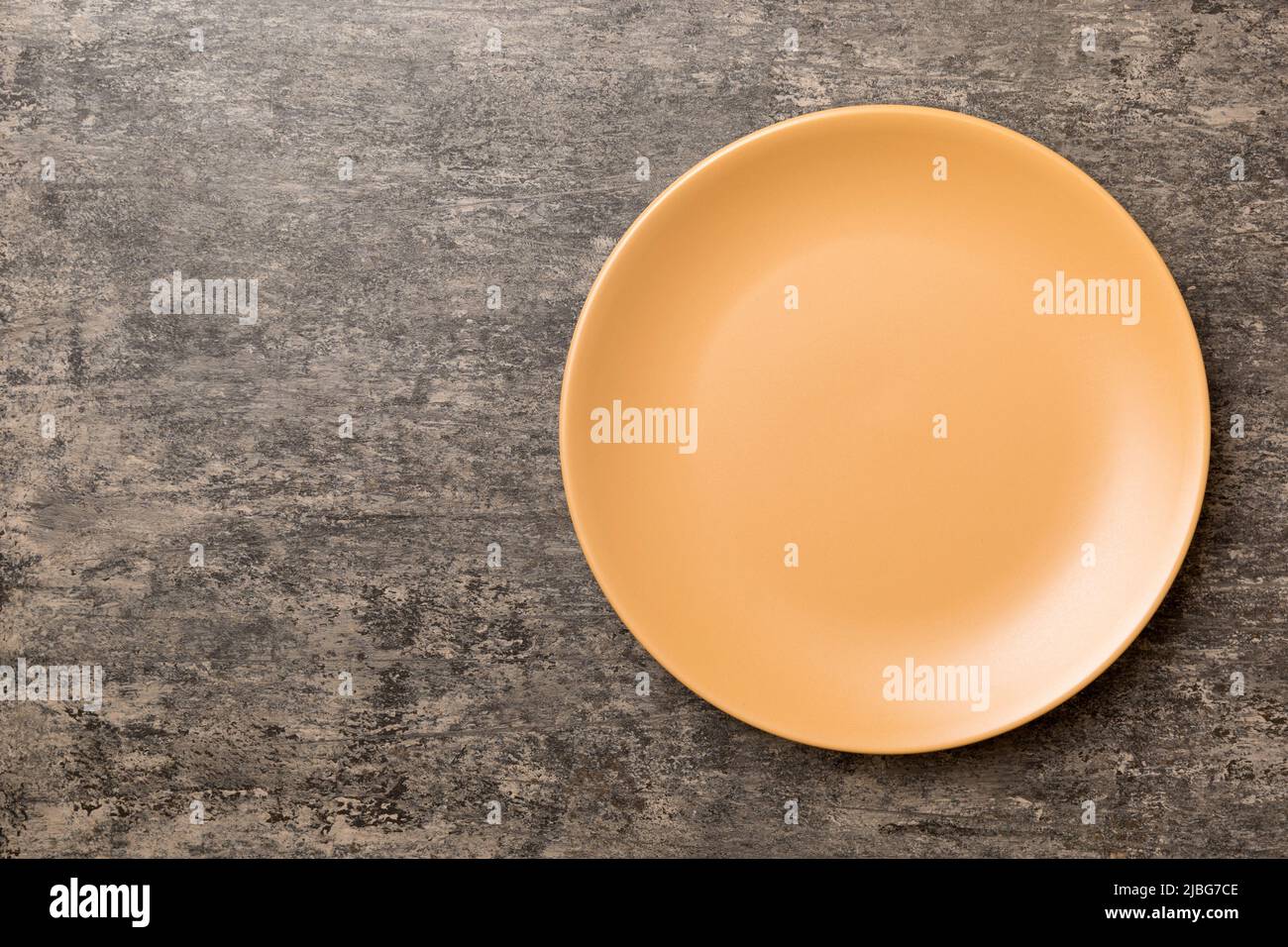 Top view of empty orange plate on cement background. Empty space for ...