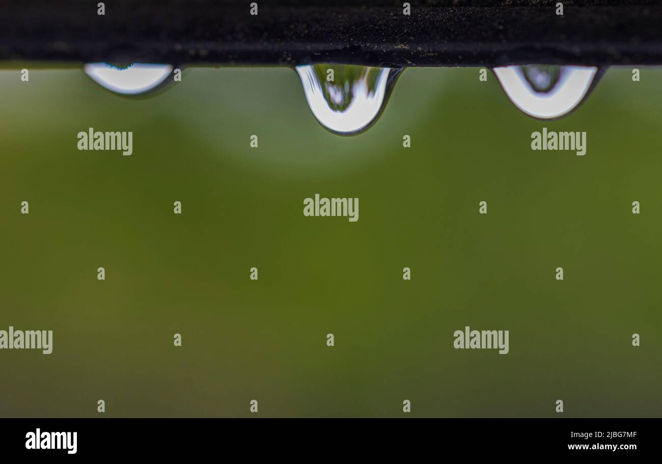 Macro view of falling raindrops from window frame of skylight during ...