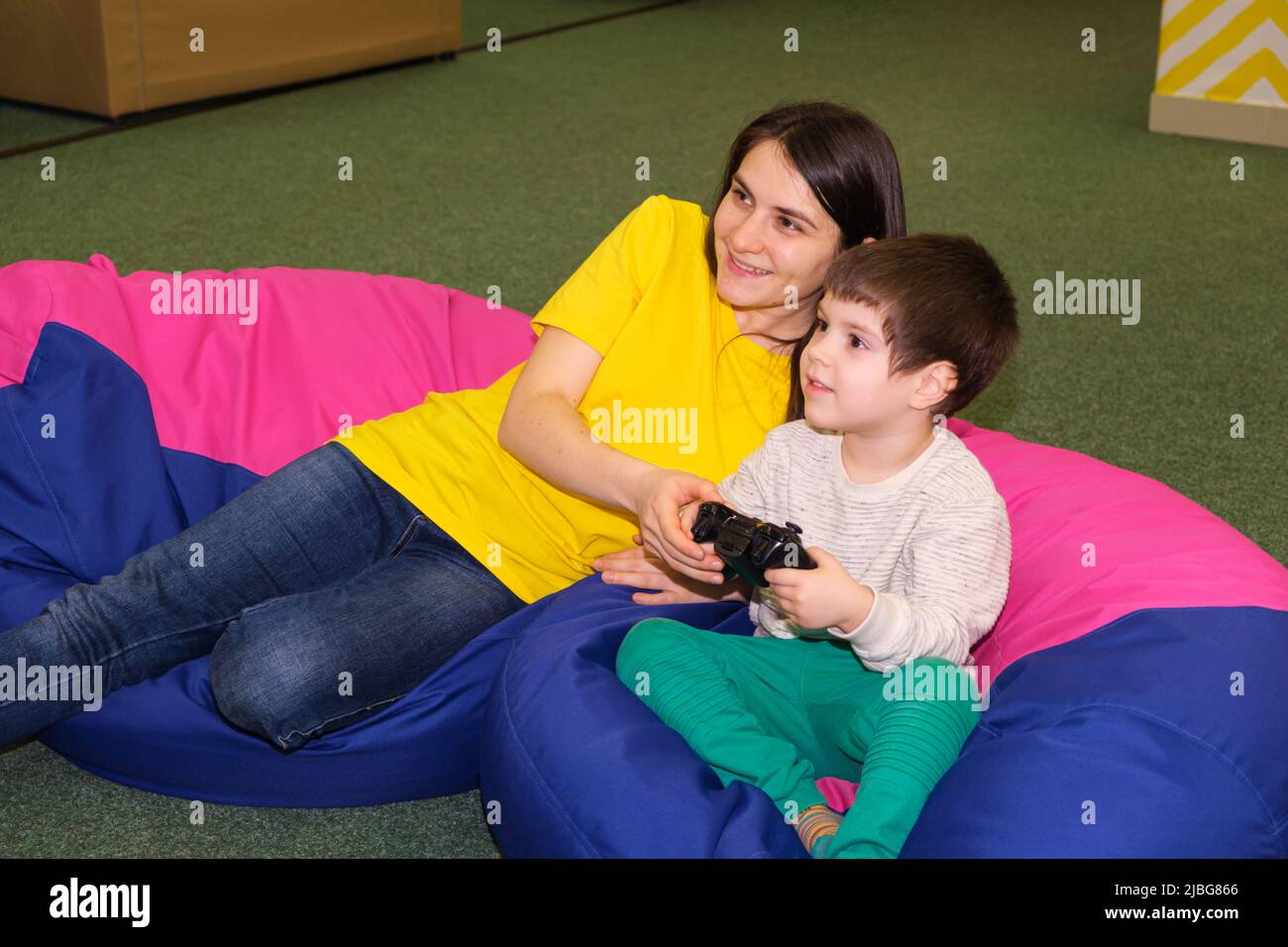 Mother and son play in the game console, the boy holds the joystick ...