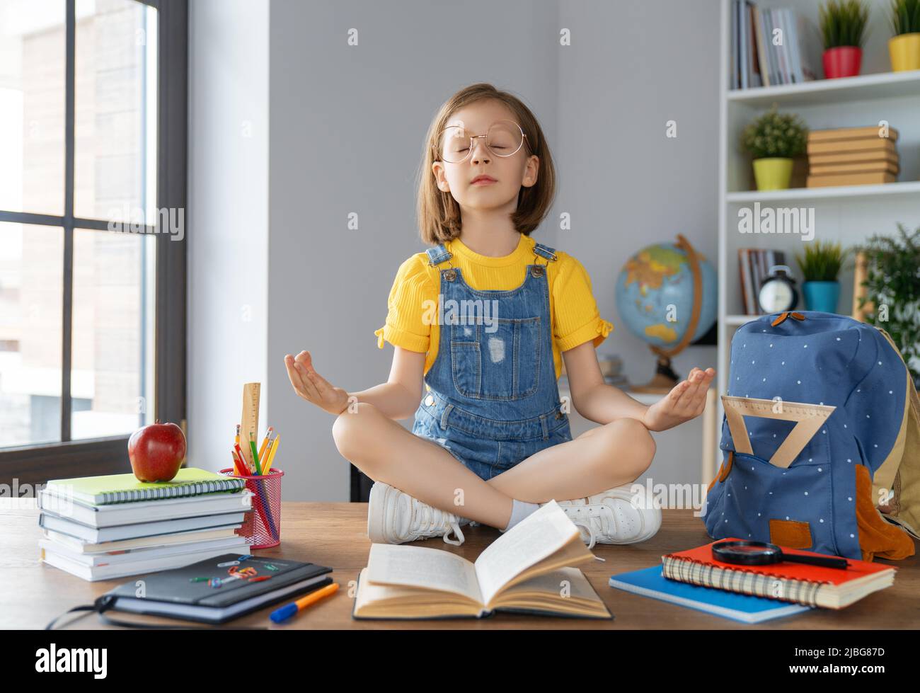 Back to school! Cute industrious child is meditating sitting at a desk ...