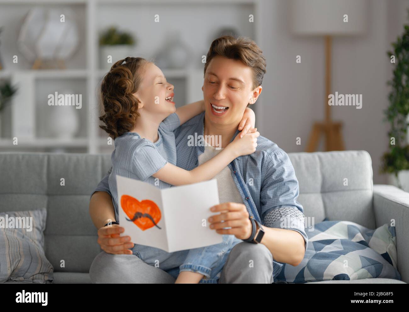 Child daughter is congratulating her father and giving him postcard ...