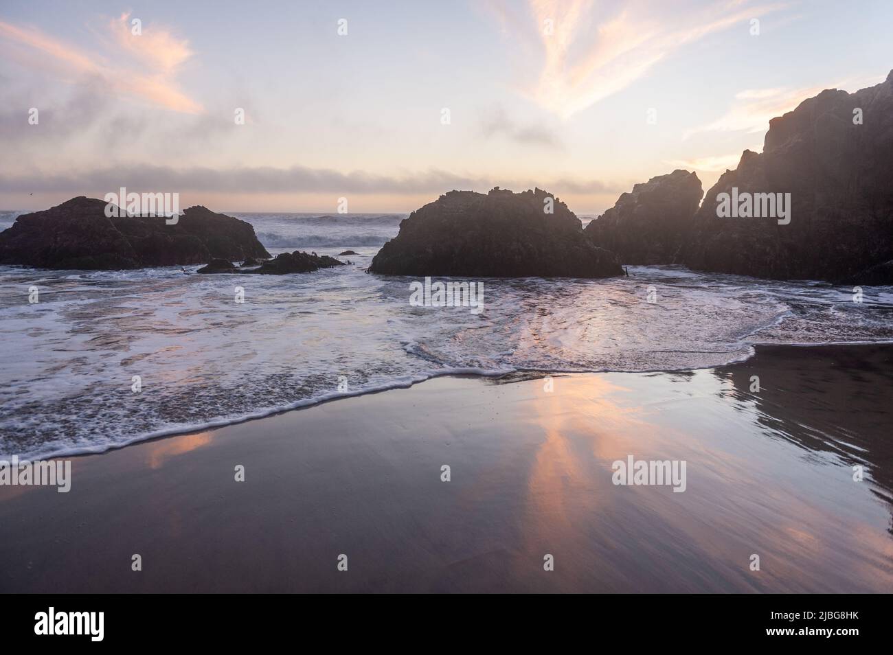 Receding ocean tides at Pfeiffer beach leaves a layer of water ...