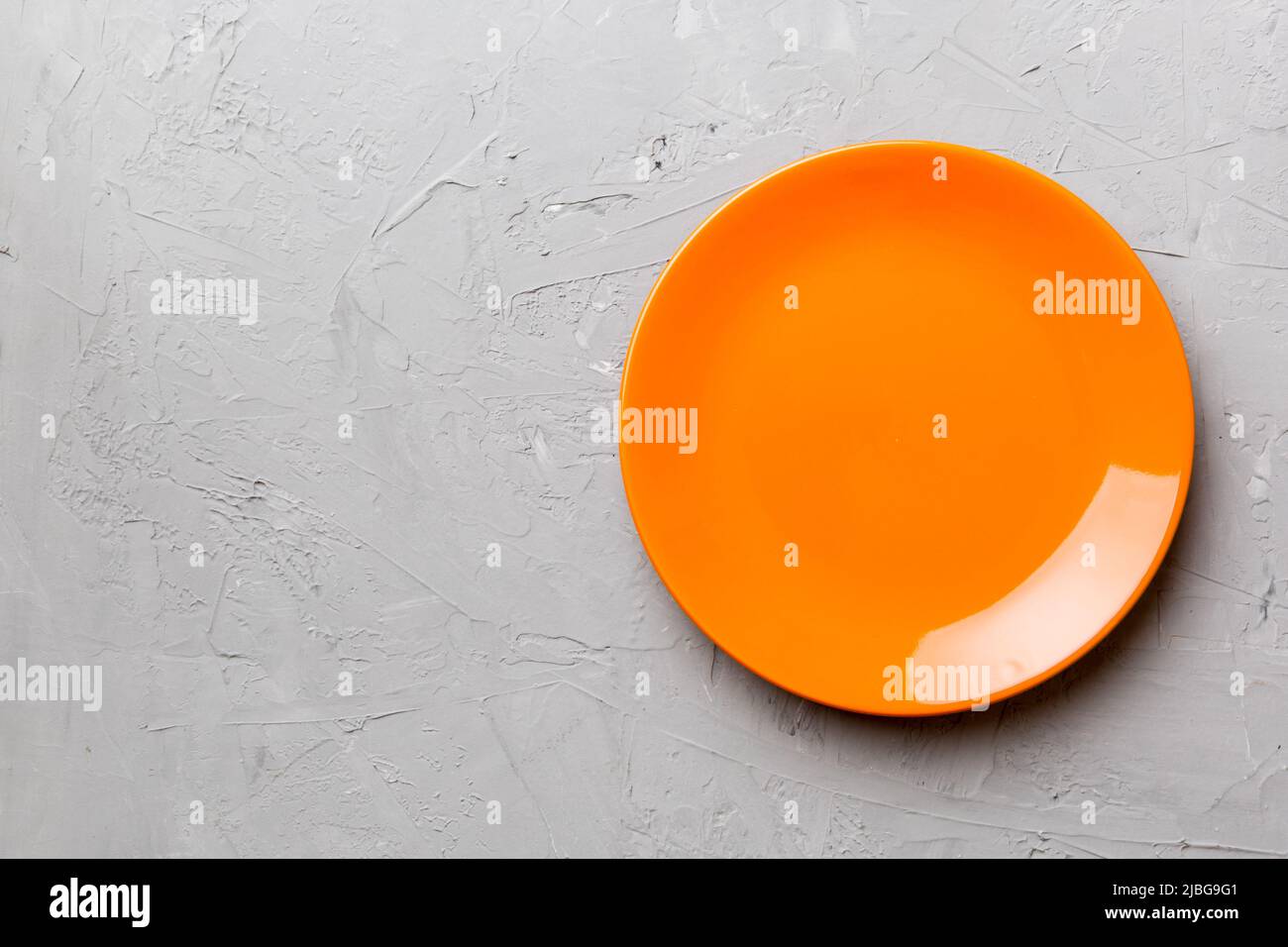 Top view of empty orange plate on cement background. Empty space for ...