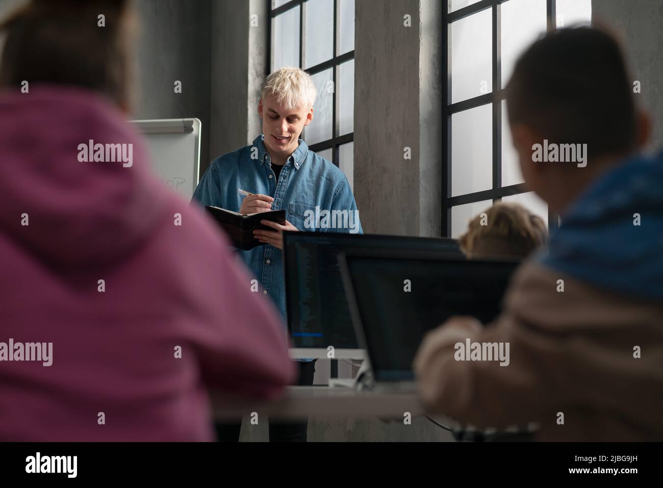 School teacher standing in front of pupils and writing notes in ...