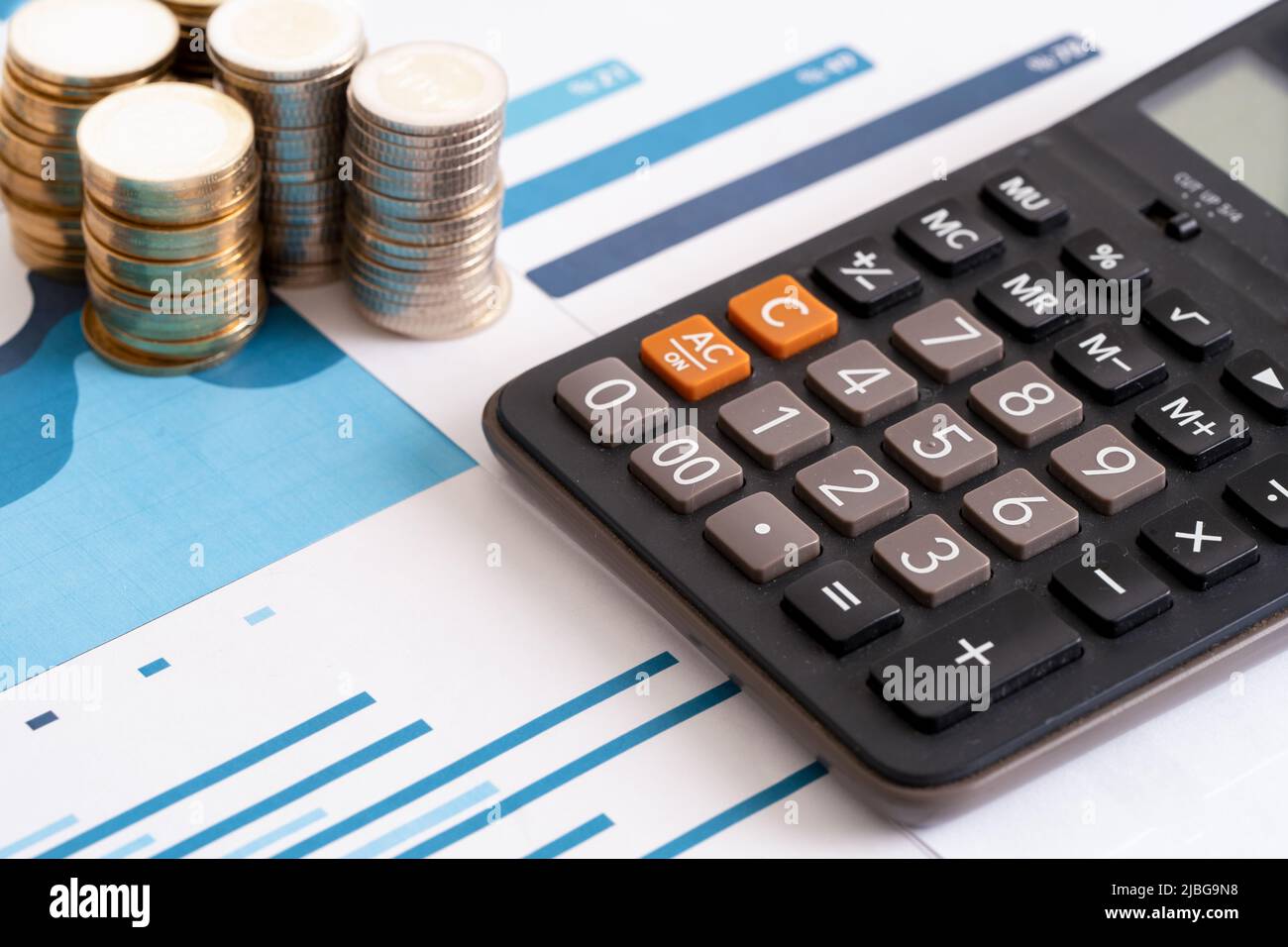 Close up photo of stack of coins and charts and stats with calculator ...