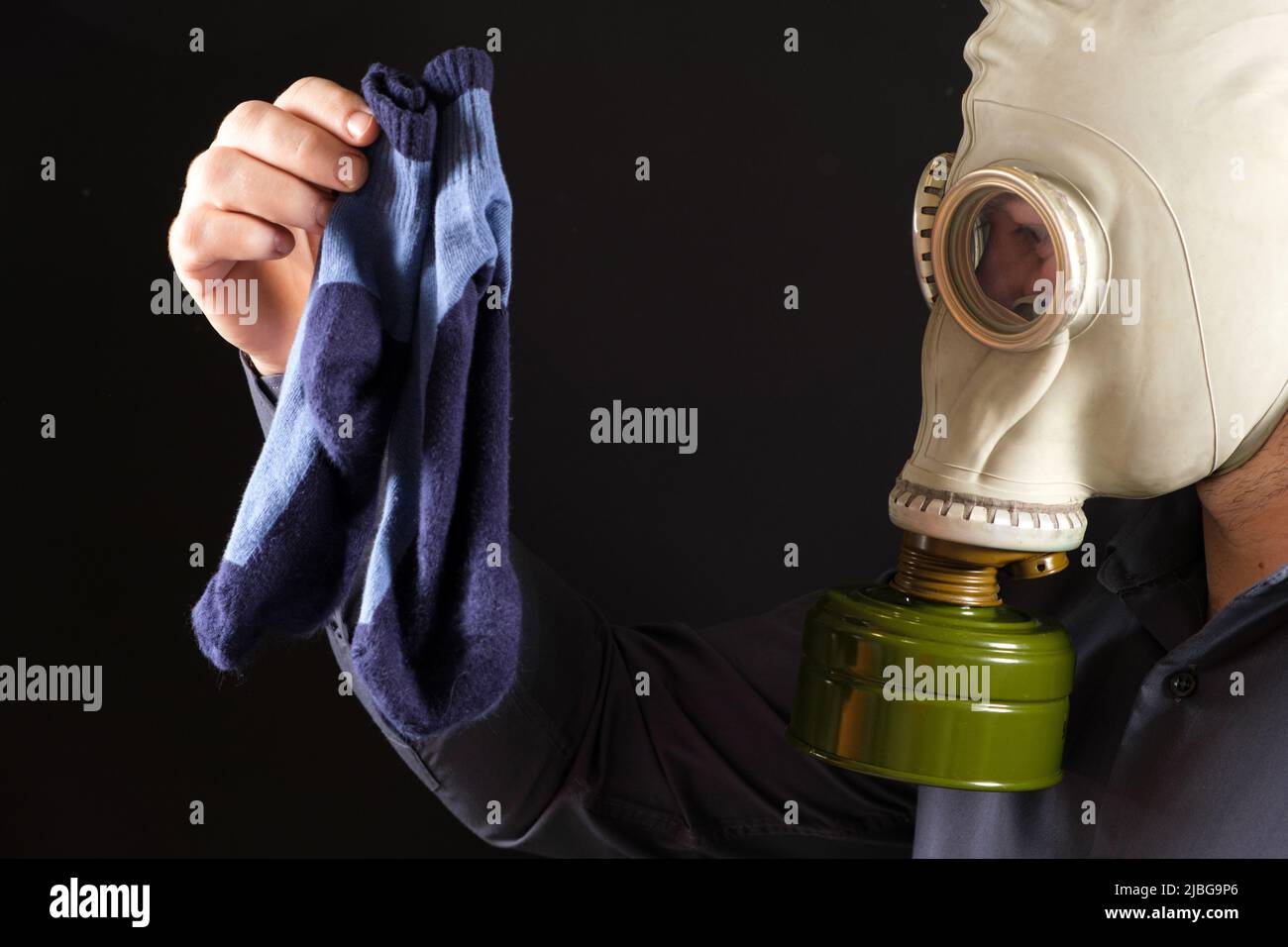 A man in a gas mask holds dirty smelly socks. The problem of unpleasant ...