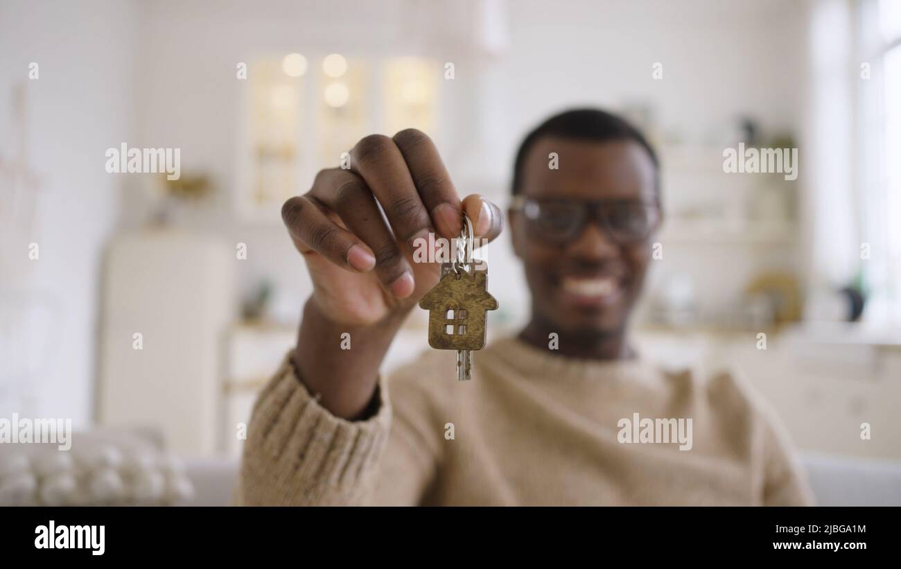Happy black man stretches out hand showing key to new apartment. Focus ...