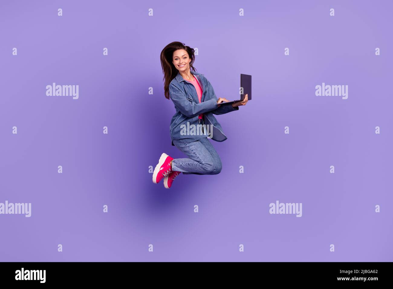 Full body portrait of excited attractive person jumping hold netbook ...