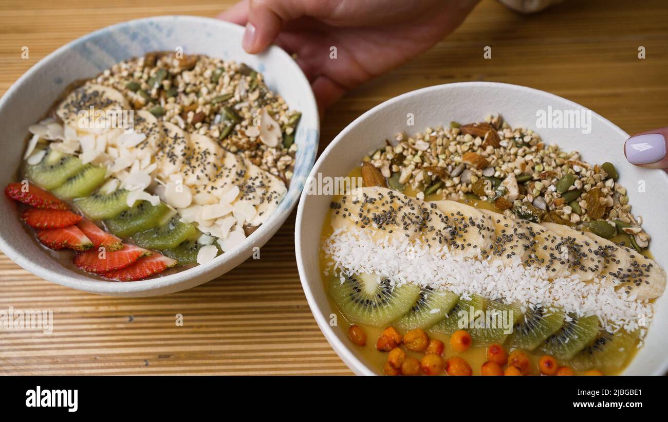 Female hands put vegan bowls on table. Healthy fruit and cereals bowls ...