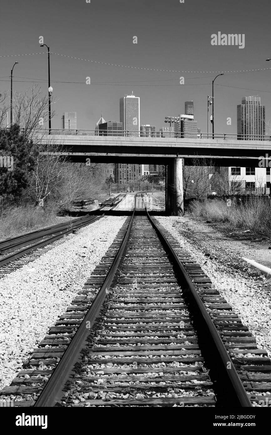 Railroad tracks going into the distance under a bridge in black and ...