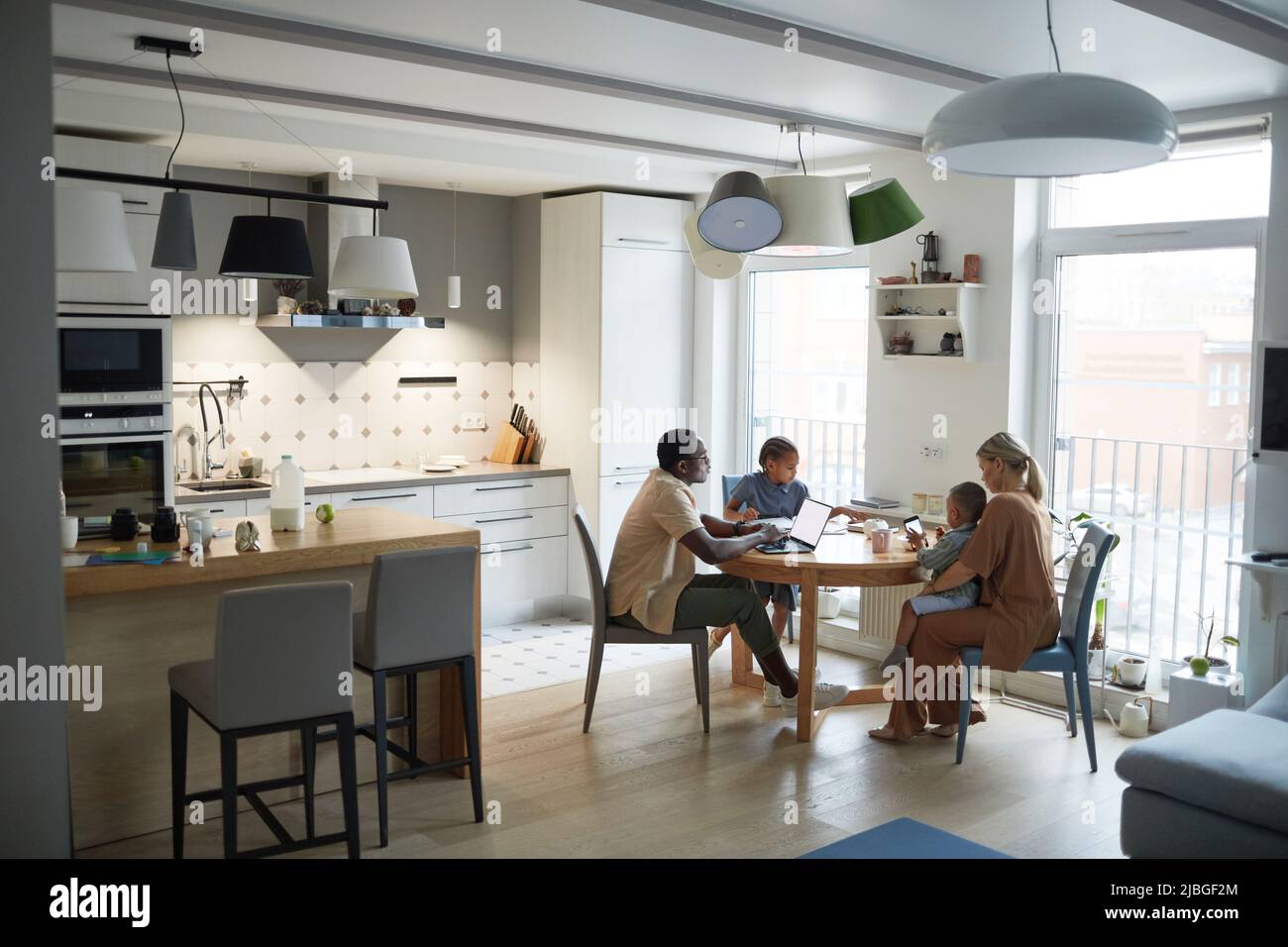 Wide angle home scene of modern multiethnic family at dinner table in ...