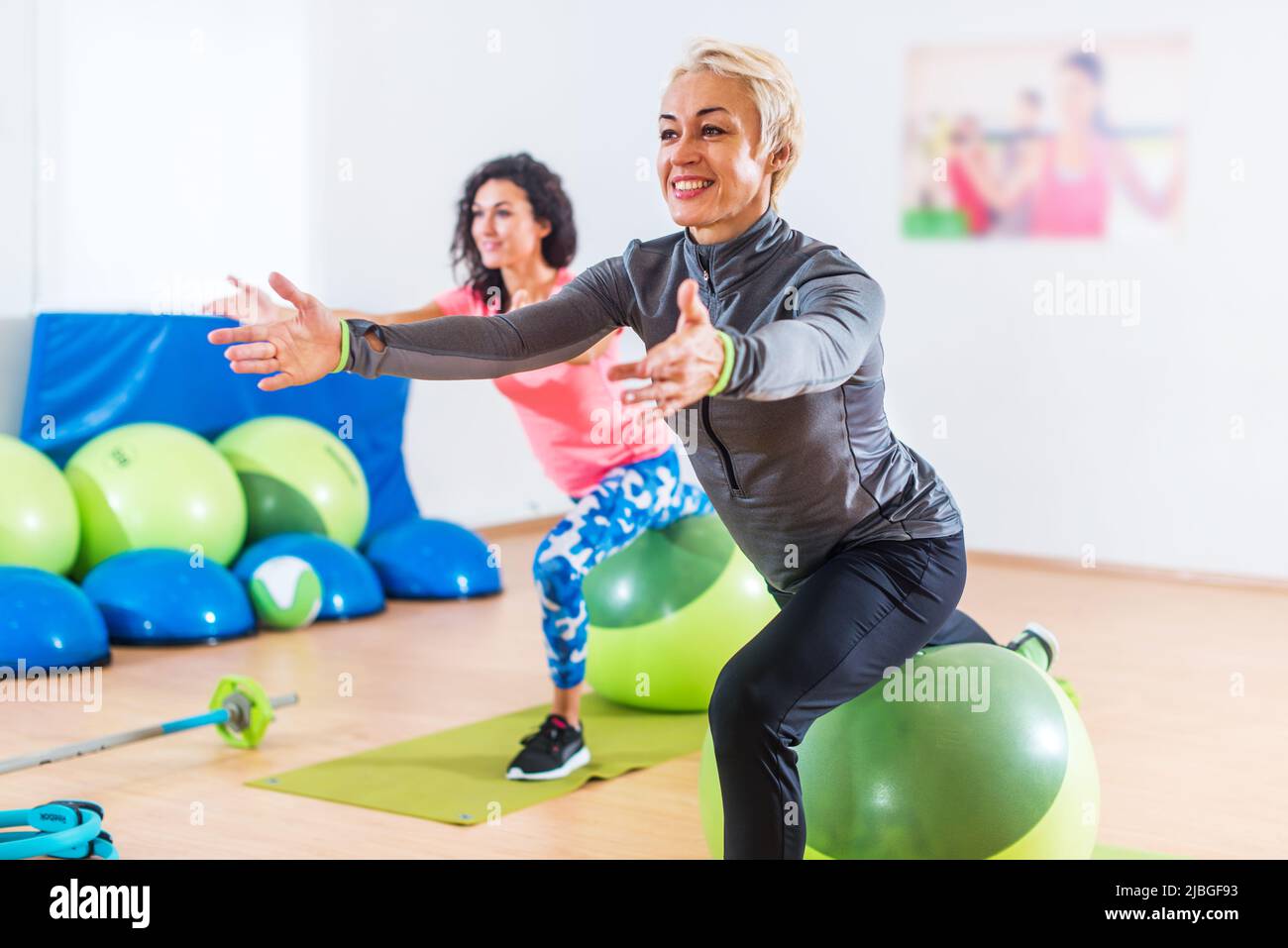 Sporty women doing stretching exercises with fitness stability ball in ...
