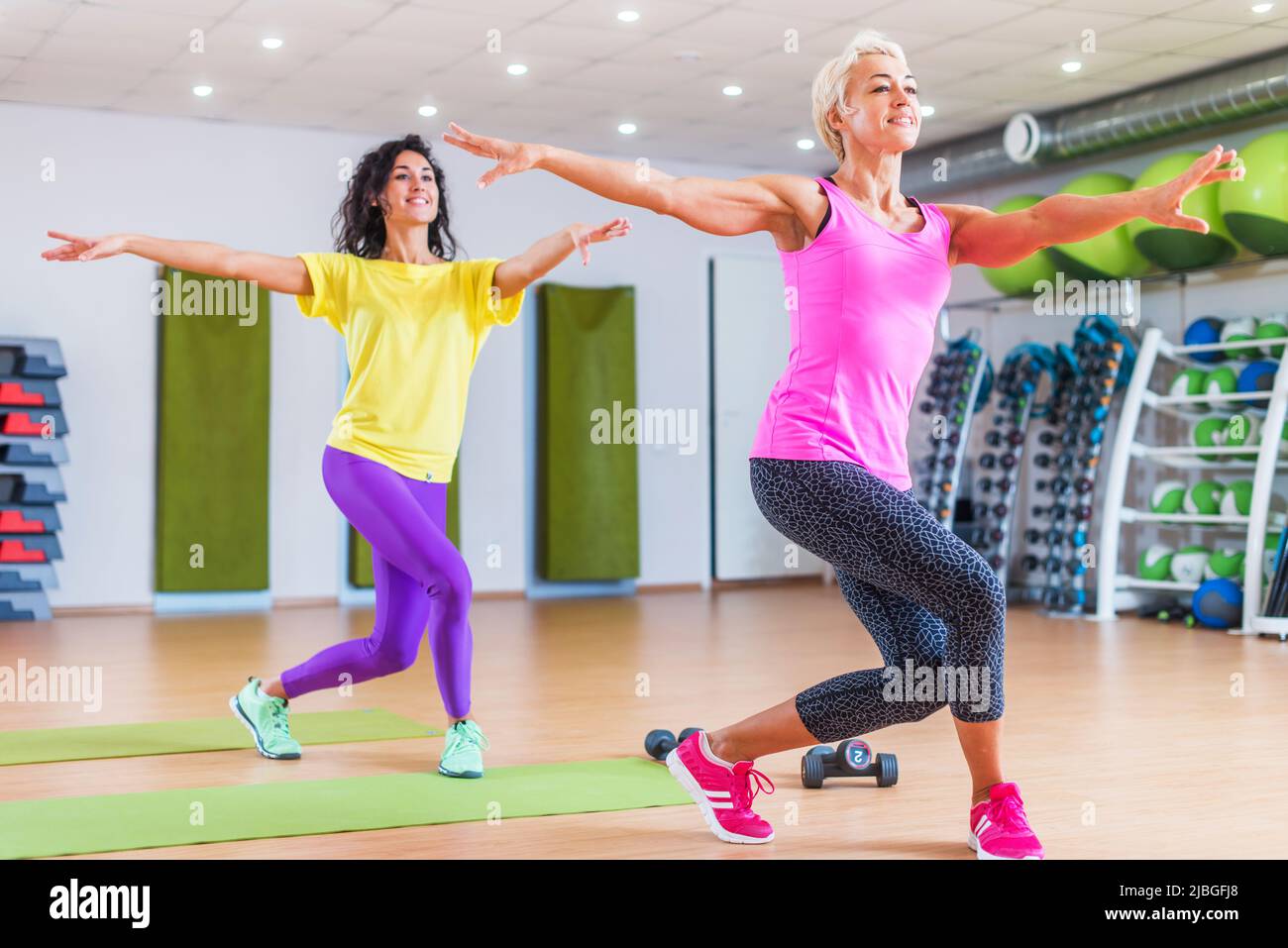Two happy female fitness models dancing Zumba, doing aerobic exercises ...