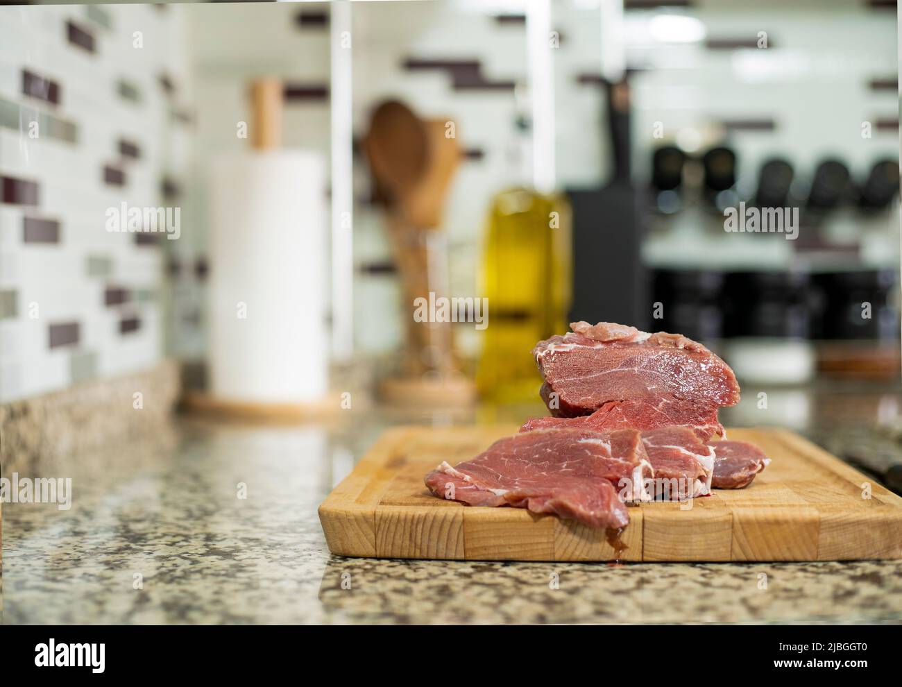 Close up photo of hand cutting meat on kitchen countertop Stock Photo ...