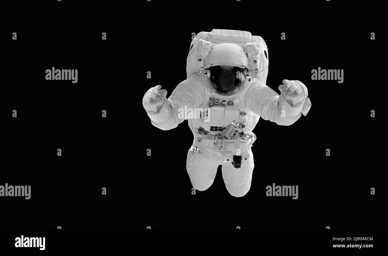 Astronaut in a spacesuit flies on black background. Hands are raised up ...