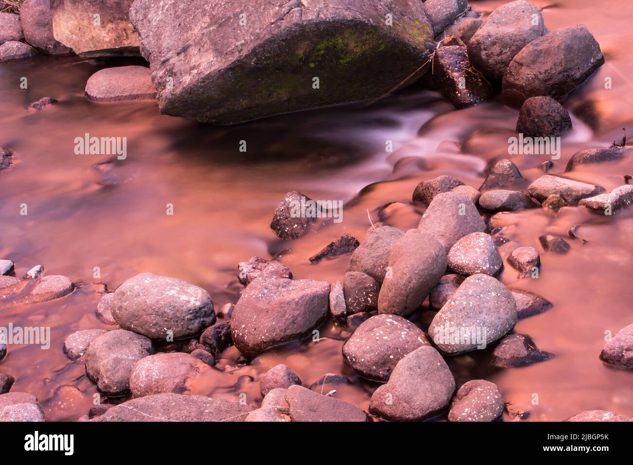 Copperish pink color of the setting sun, Reflecting in the fast flowing ...