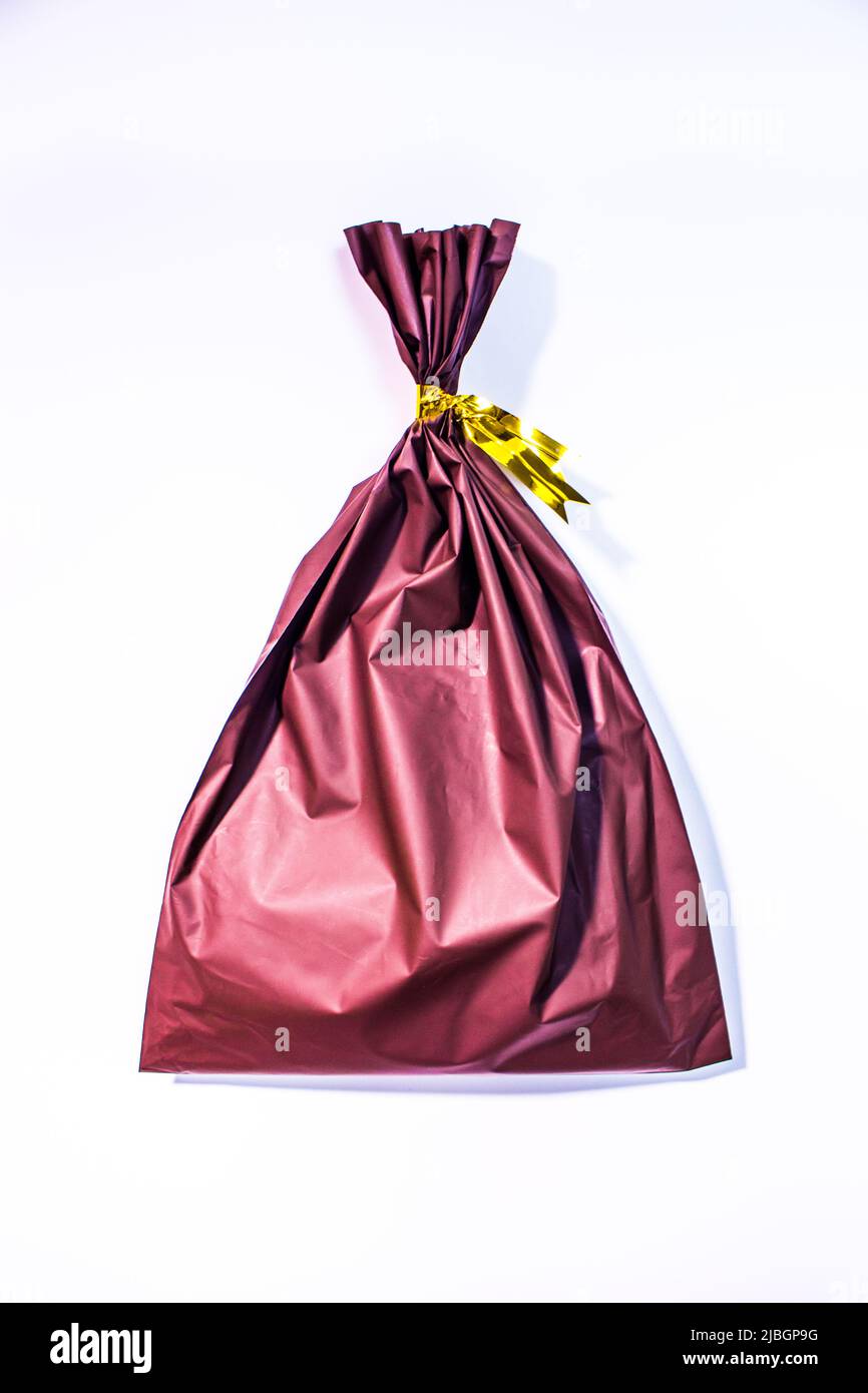 Small wrapped bag with gift. The bag in image is tied with golden ...