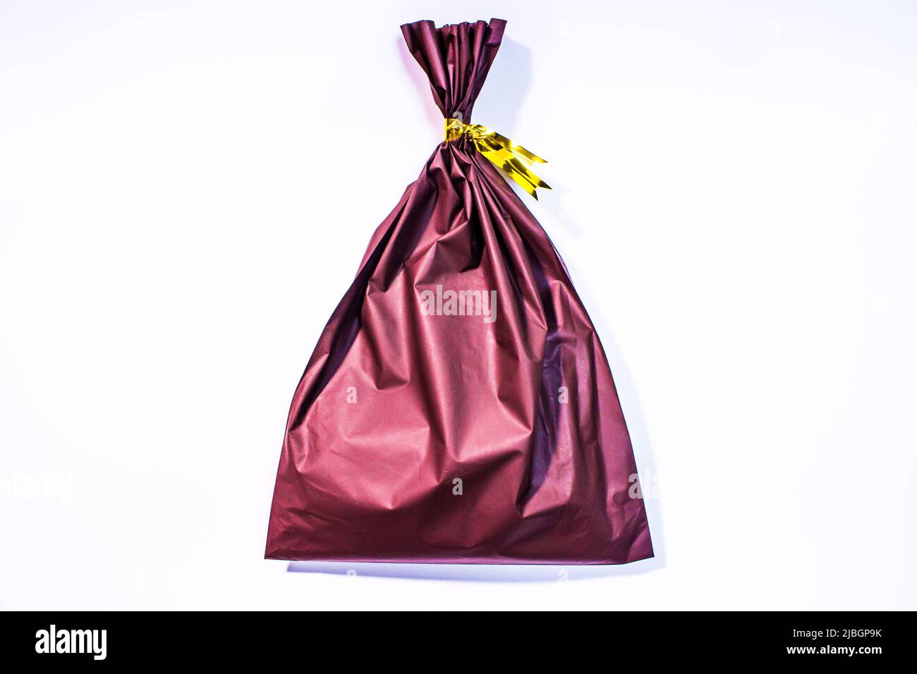 Small wrapped bag with gift. The bag in image is tied with golden ...