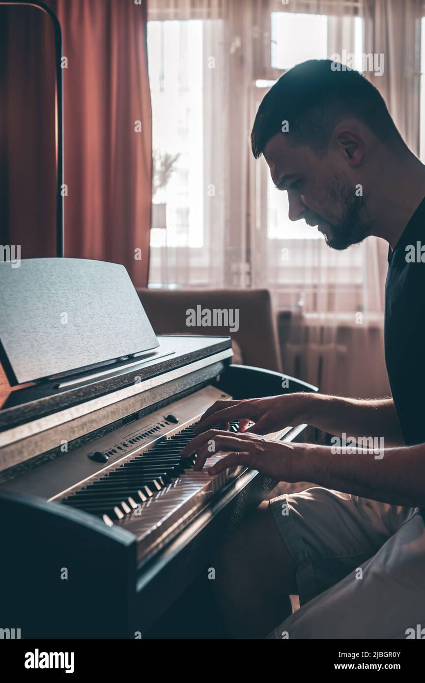 Male musician plays the electronic piano in the room Stock Photo - Alamy