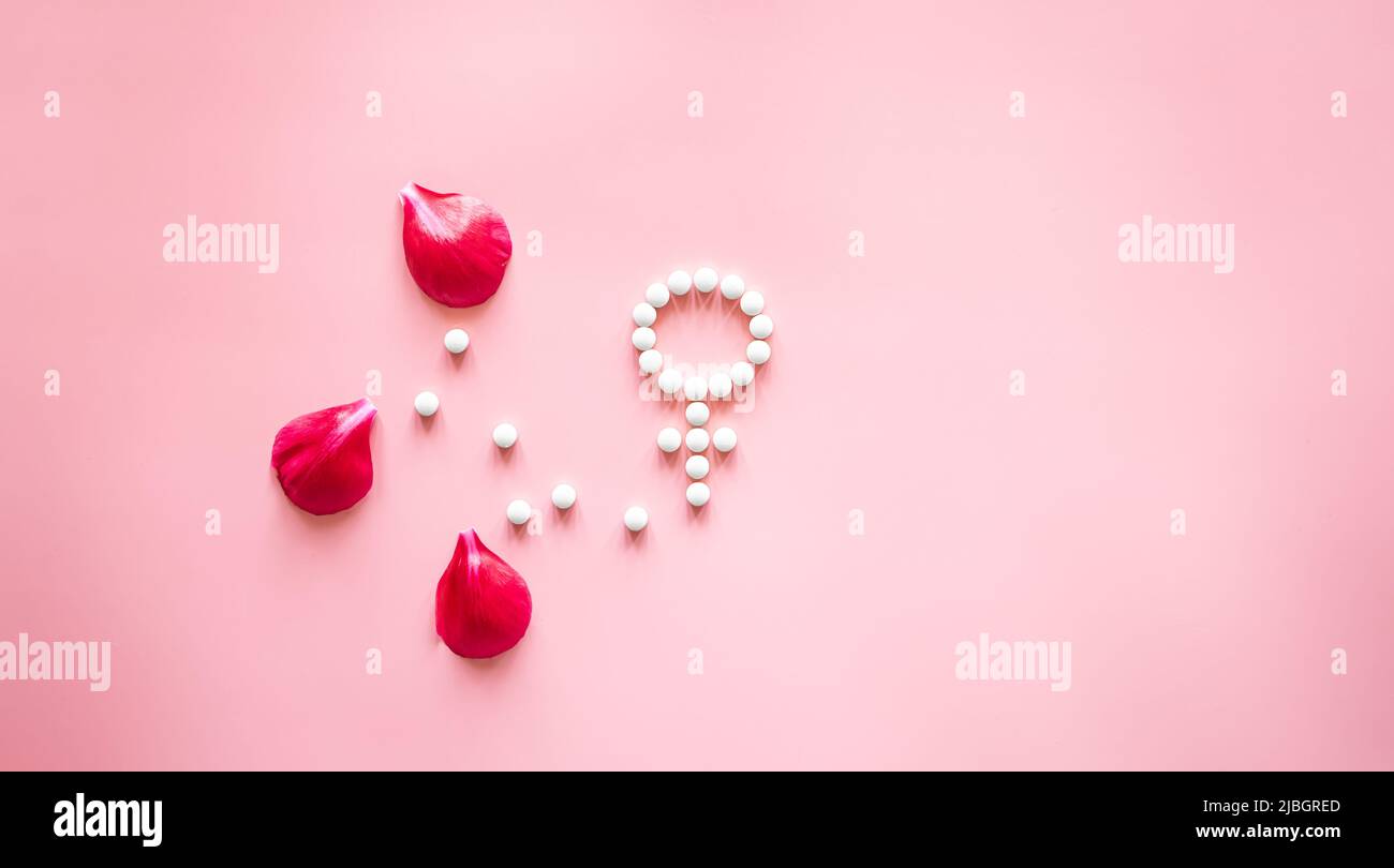Gender Venus symbol made of pills, and peony flower petals on a pink ...
