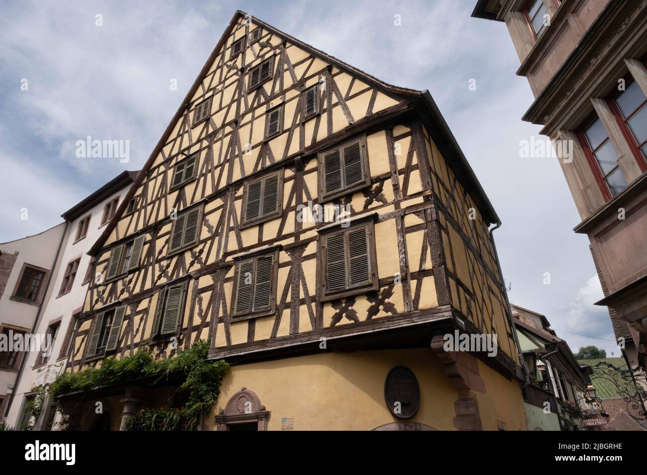 Facade of a colorful traditional half-timbered yellow house, named 'Le ...