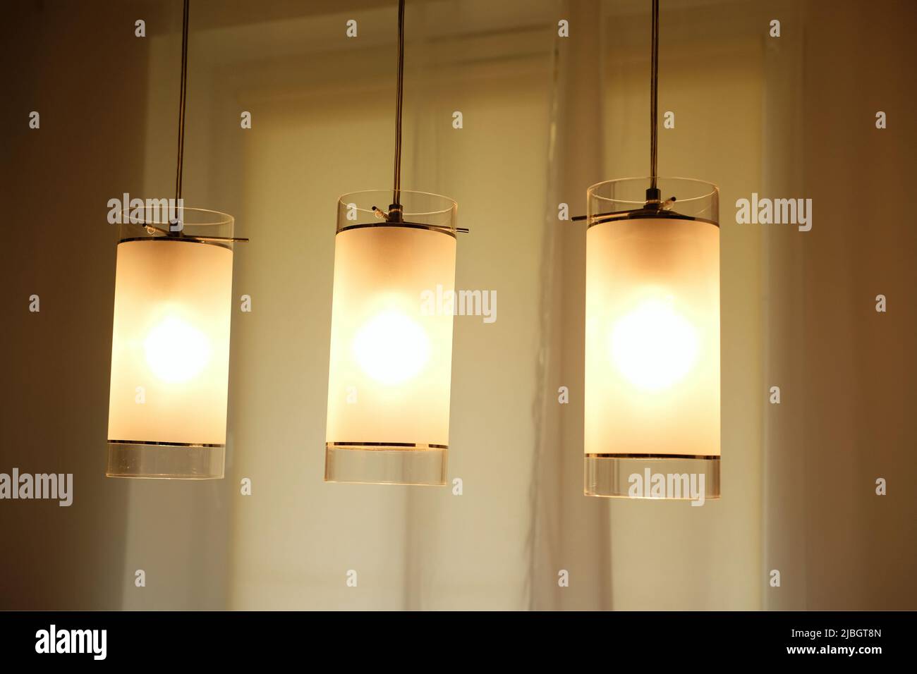 three glowing lamps lit over table Stock Photo - Alamy