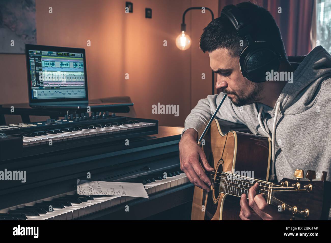 Male musician plays the guitar at home in the workplace near the ...