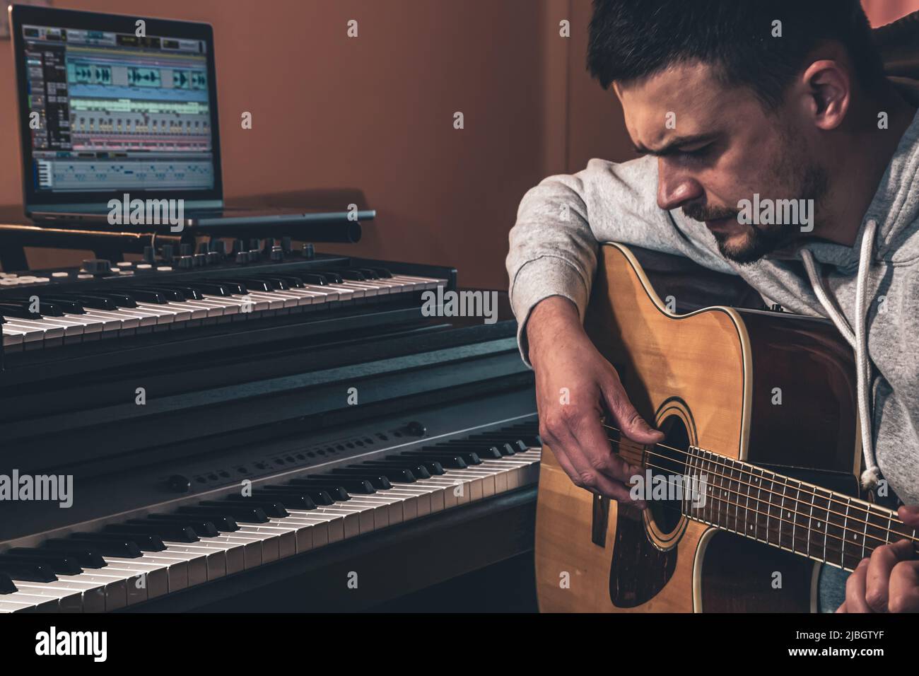 Male musician plays the guitar at home in the workplace near the ...