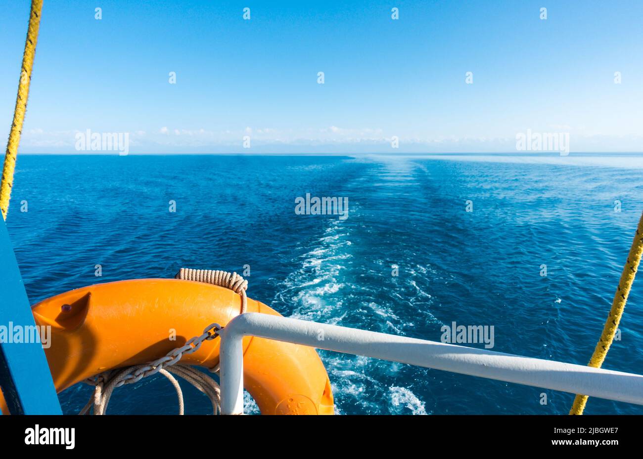 Ship's stern, lifeline. Footprint on the water from the boat. Blue ...