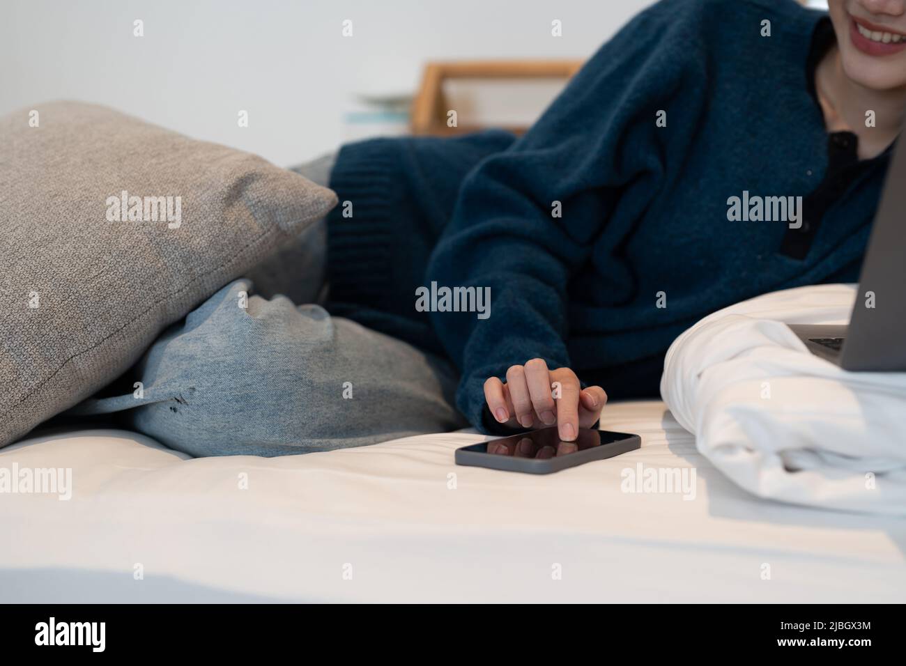 Happy young asian woman using mobile phone while sitting a couch at ...