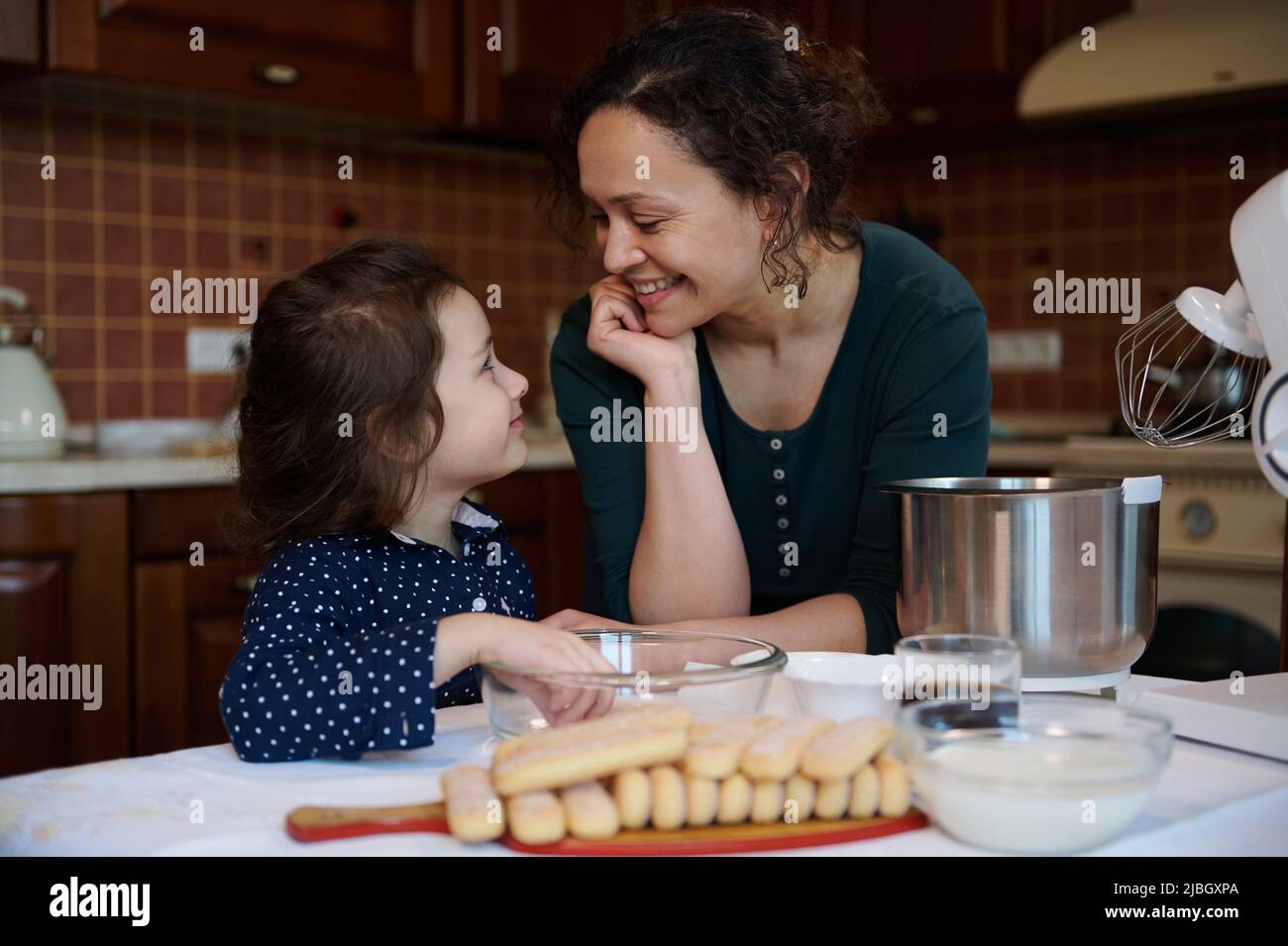 Loving mother and her cute daughter enjoying making Italian Tiramisu ...