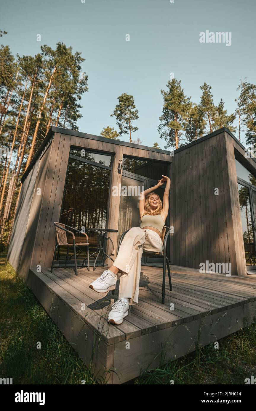 Happy lady seated on the veranda of her cottage Stock Photo - Alamy