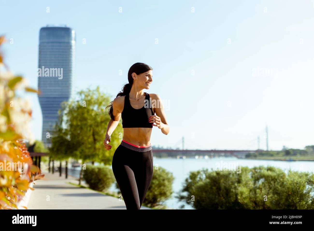 Pretty young woman taking running exercise by the river promenade Stock ...