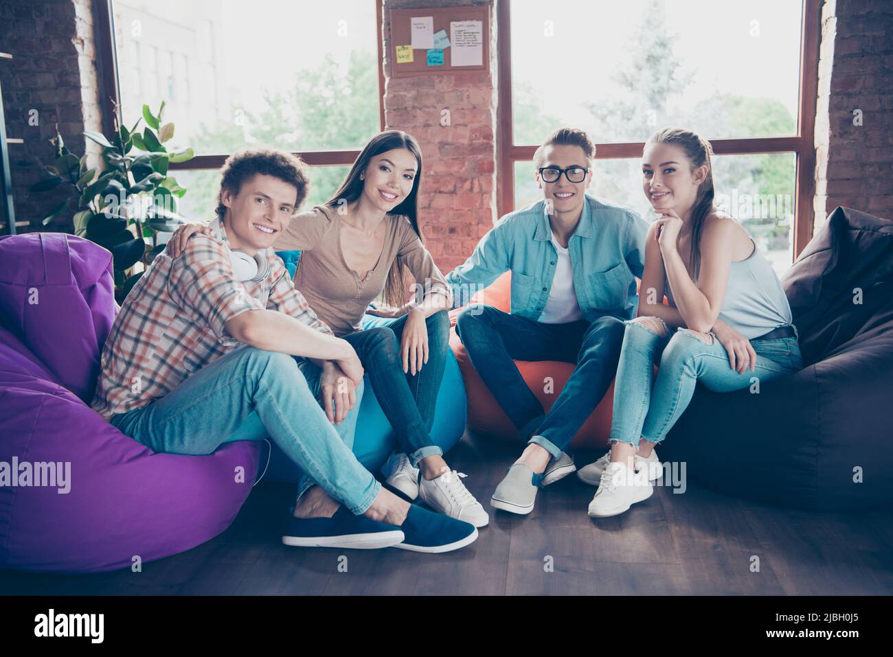 Photo of cute good mood workers group sitting dorm bean bags having ...